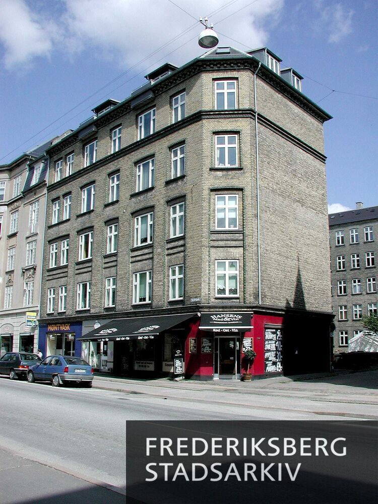 Ejendommen med butiksfacader til Hansens Mad & Vin, reklame og naboejendommens tårn aftegnet som ...